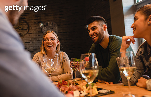 Group of young friends having fun in restaurant, talking and laughing ...