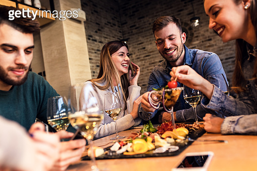Group of young friends having fun in restaurant, talking and laughing ...