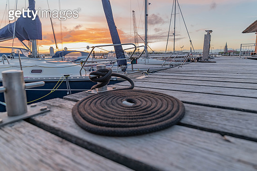 Mooring line with knotted and tied up on wooden pier. Sailing boot tied ...