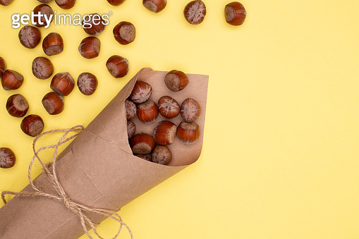 Hazelnuts screw on a yellow background. Nuts wrapped in eco kraft paper ...