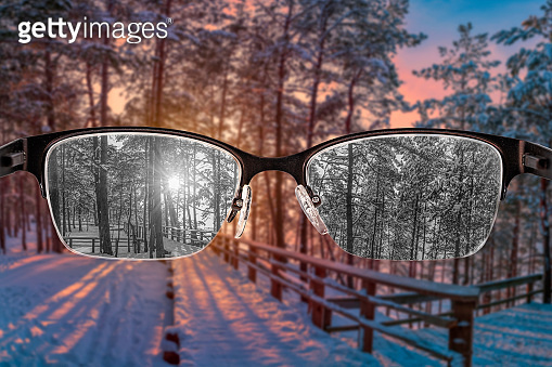 Looking through glasses to black and white sunset in winter forest view ...