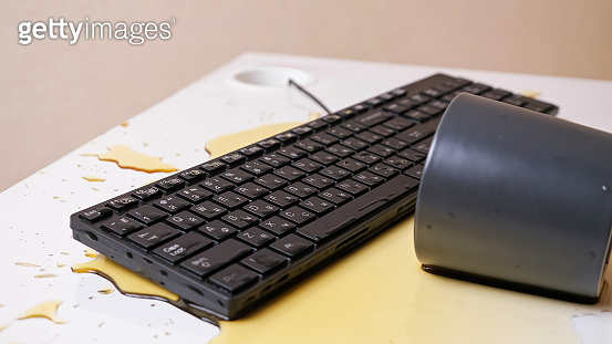 Close-up of a coffee-soaked keyboard with a cup overturned nearby 이미지 ...