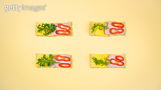 Four rectangular sandwiches with cheese, ham, arugula sprigs and slices ...