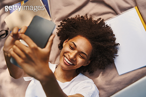 Gladsome pretty lady smiling tocamera while lying on a blanket and ...