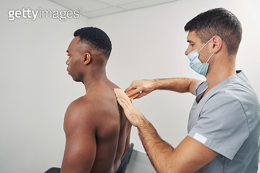 Experienced physiotherapist using kinesiology taping technique for ...