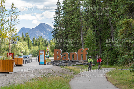Banff Town Sign in summer time. Tourist cycling in Banff Legacy Trail ...
