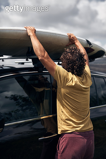Windsurfer and camper packing and unpacking from a car's roof rack in ...