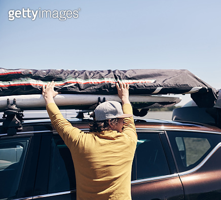 Windsurfer and camper packing and unpacking from a car's roof rack in ...