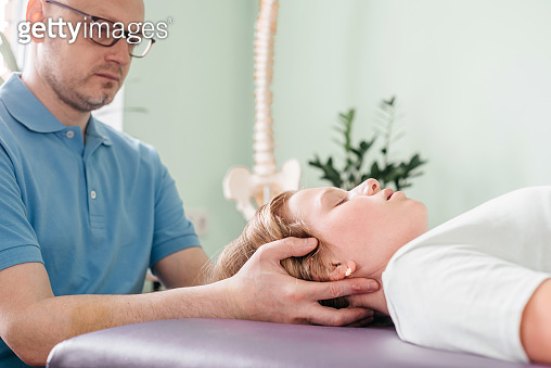 Massage therapist performing cranial sacral therapy on a female child ...