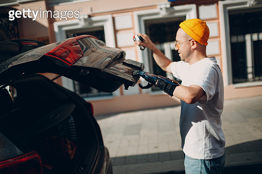 Young disabled man with artificial prosthetic hand closing back trunk ...