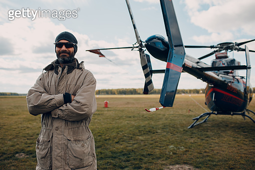 Portrait of helicopter pilot standing near vehicle in field airport ...