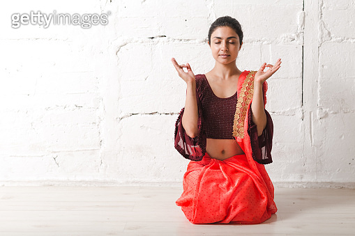 Young adult indian woman in sari meditating yoga lotus pose zen like ...
