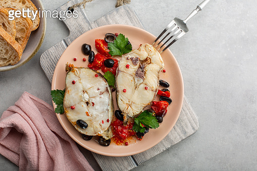 Eating cod fish steaks baked with tomatoes and black olives. Healthy ...