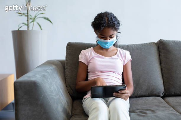 Mixed race girl wearing face mask using tablet in hospital waiting room 이미지 (1315363172) - 게티이미지뱅크