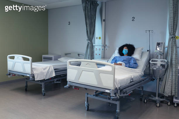 African american female patient lying in hospital bed wearing face mask ...
