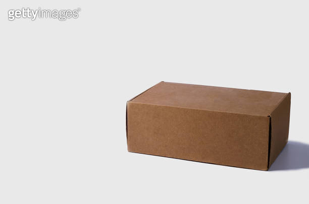 A closed cardboard box stands on a light background. Medium brown box with copy space 이미지 ...