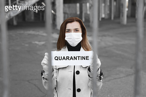 A woman behind bars in isolation holds a placard reading "quarantine ...