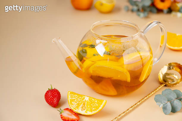 Colorful fruit tea in glass tea pot with fresh fruit slices and ...