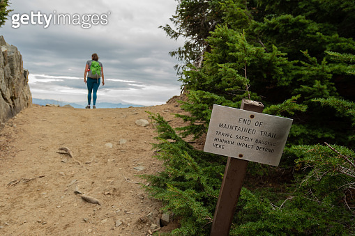 Woman Stands at Peak Just Past End of Trail Sign 이미지 (1296054678) - 게티이미지뱅크