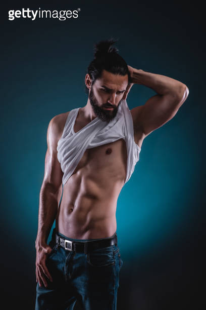 Studio portrait of a beautiful masculine bearded shirtless man showing ...