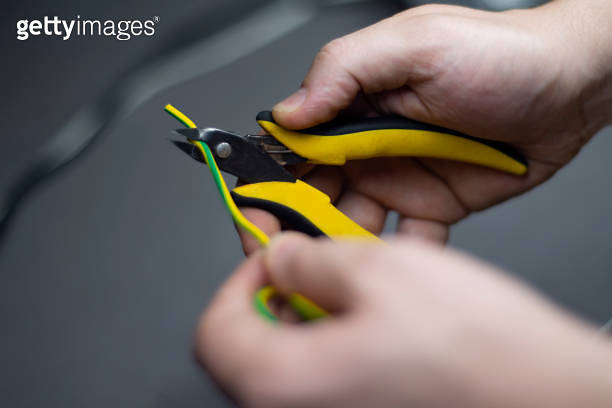 A man hand stripping a wire with yellow metal nippers (1337100779) - 게티 ...