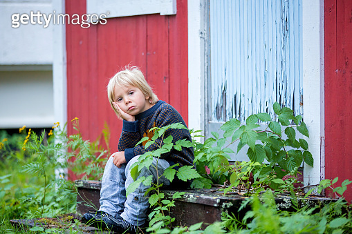 Sad little child, preschool boy, sitting on stairs in front of old ...