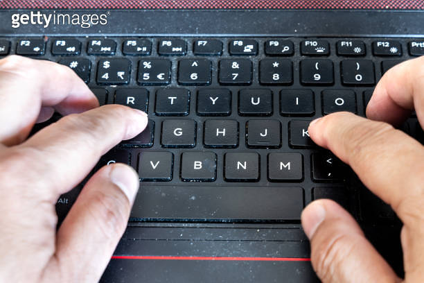 Fingers typing on laptop computer keyboard laced with dusk, particles ...