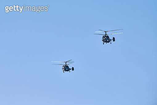 Two military helicopters flying in bright blue sky performing ...