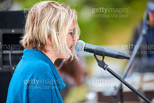 Female singer singing into microphone on stage at street concert ...