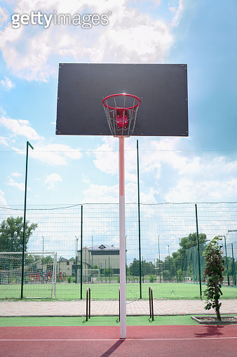 Basketball backboard with a basket made of iron chains on a sunny day ...