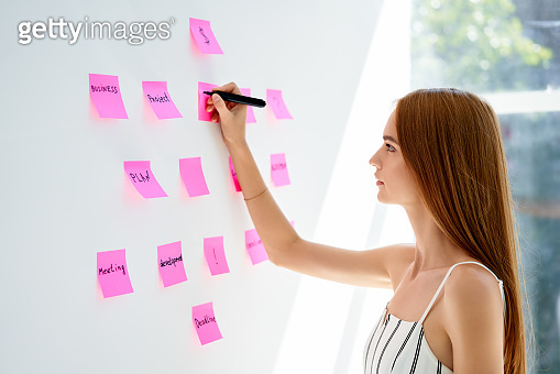 Attractive concentrated business woman using sticky notes to write and ...