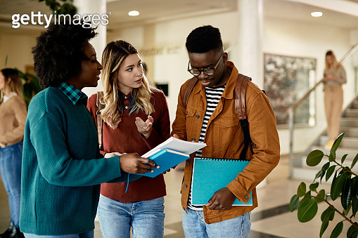 Group of college friends talking while going through lecture in a ...
