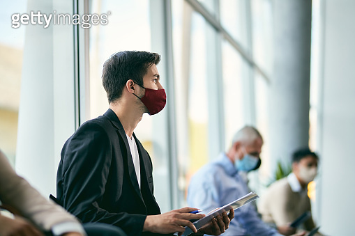 Businessman with face mask employment documents while sitting in ...