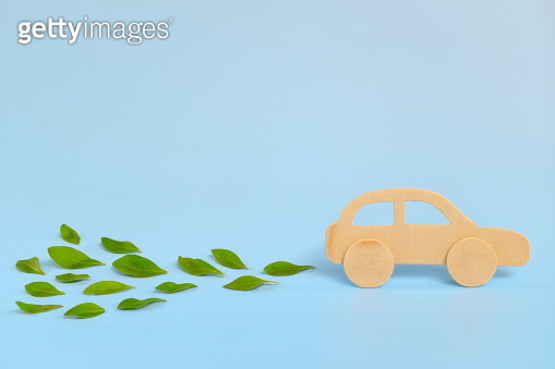 Wooden car model emitting fresh green leaves on blue background ...