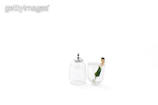 A tiny model of a young girl standing inside a plastic container. Covid ...
