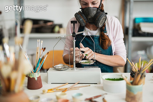 Caucasian woman with powder and scale working inside ceramic pottery ...