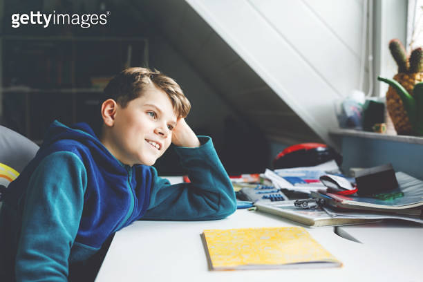 Hard-working happy school kid boy making homework during quarantine ...