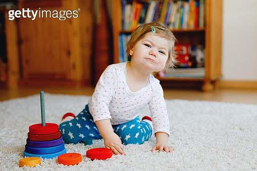 Upset crying baby girl with educational toys. Sad tired or hungry alone ...