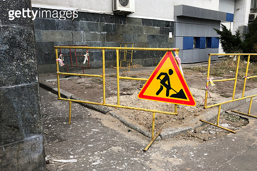 road repair sign and yellow iron fences are on a problem area with pits ...