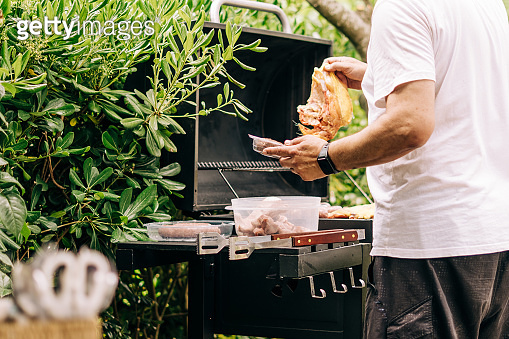 Man grilling meat on a barbecue various types of meat, chicken ...