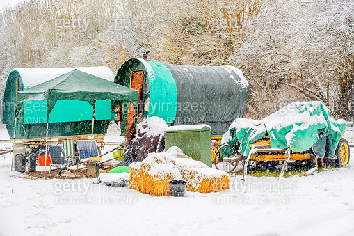 A gypsy travellers camp with wagons covered in snow ice and frost on a ...