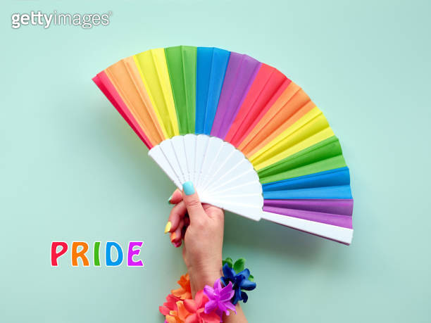 LGBTQ community pride. Hand with colored fake nails holds rainbow fan ...