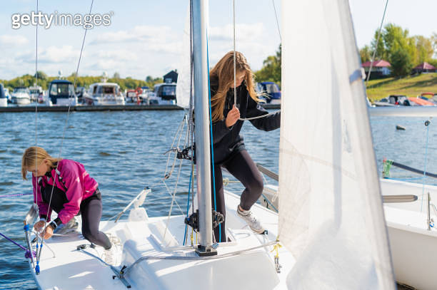 Cute blondes on the pier prepare a sailing yacht for a regatta, pull ...