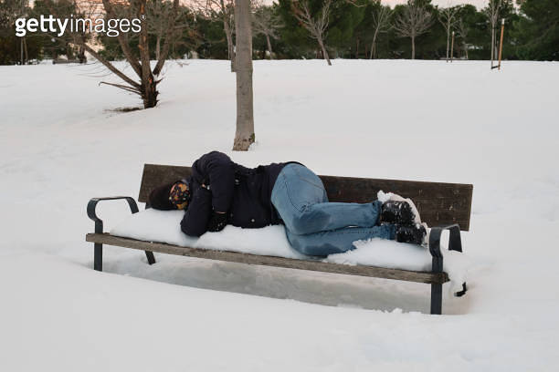 Unrecognizable homeless man sleeping on bench in snowy cold winter ...