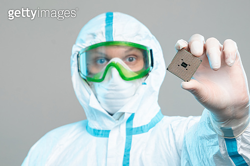 A man in sterile form holds a microprocessor in his hands, close-up ...
