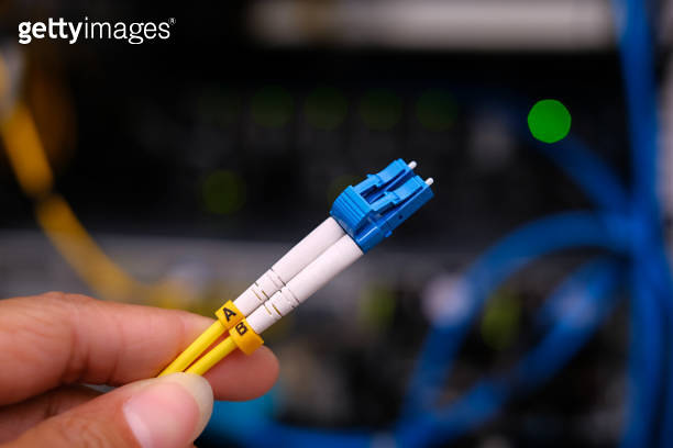 Close up fiber optic cable and blur network router switch on background ...