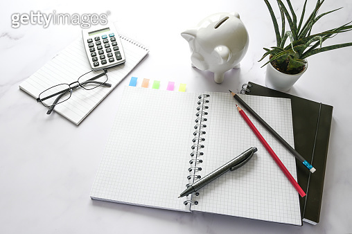 Office desk with a blank notebook, piggy bank, calculator and ...