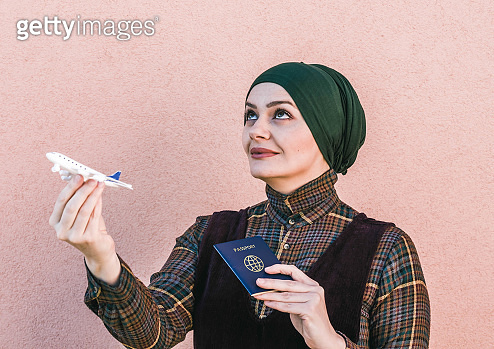 Muslim woman in hijab clothes hold passport and plane toy (1355679414 ...