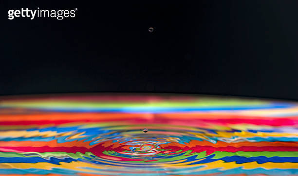 Water drop making ripple on multicolored base and black background 이미지 ...