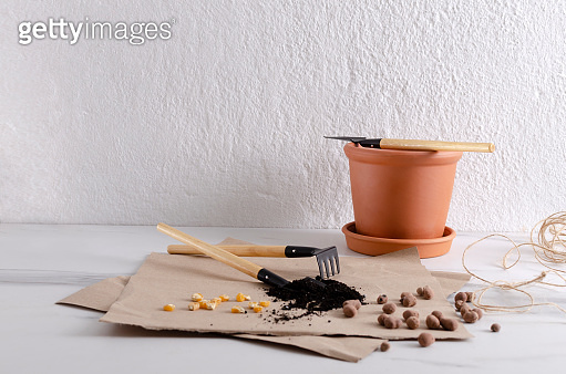 Shovel, rake, soil on the paper, clay pot on the white table against ...